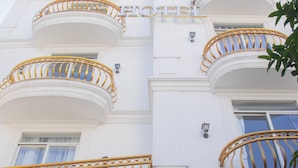 Um hotel com vários andares, varandas, janelas amplas e uma placa grande.