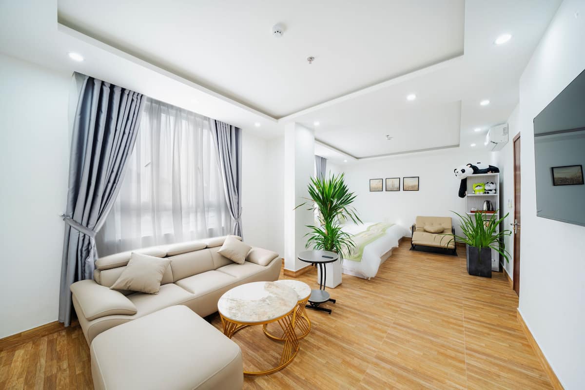 Uma sala de estar moderna com um sofá, uma mesa de centro, uma mesinha lateral e um vaso com planta.