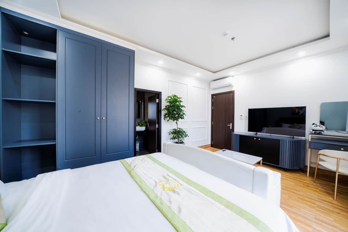 Um quarto moderno com cama, escrivaninha, televisão e guarda-roupa.