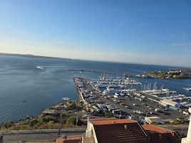 Uma marina com barcos atracados, um píer que se estende para a água e uma estrada que leva à marina.