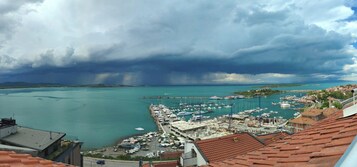Uma marina costeira com barcos atracados, um porto e vista para o mar sob um céu nublado.