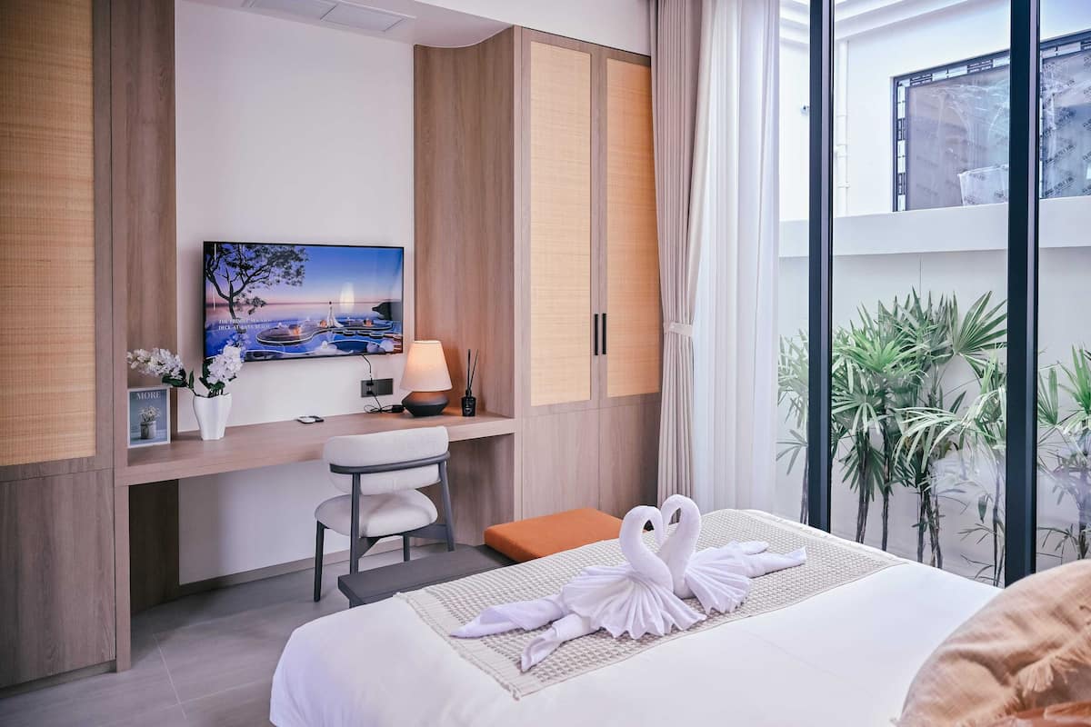 Quarto de hotel com cama, escrivaninha, cadeira, televisão e vista para o exterior.