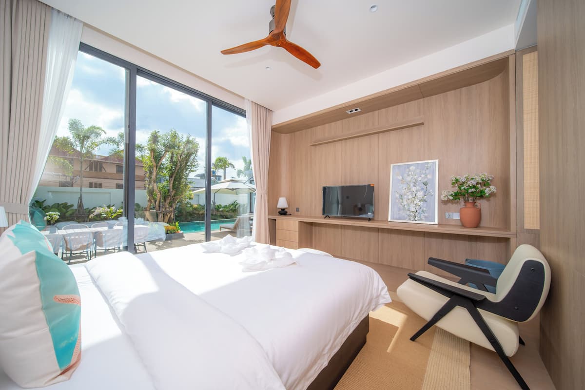 Quarto de hotel com uma cama grande, uma escrivaninha com cadeira, televisão e vista para o exterior.