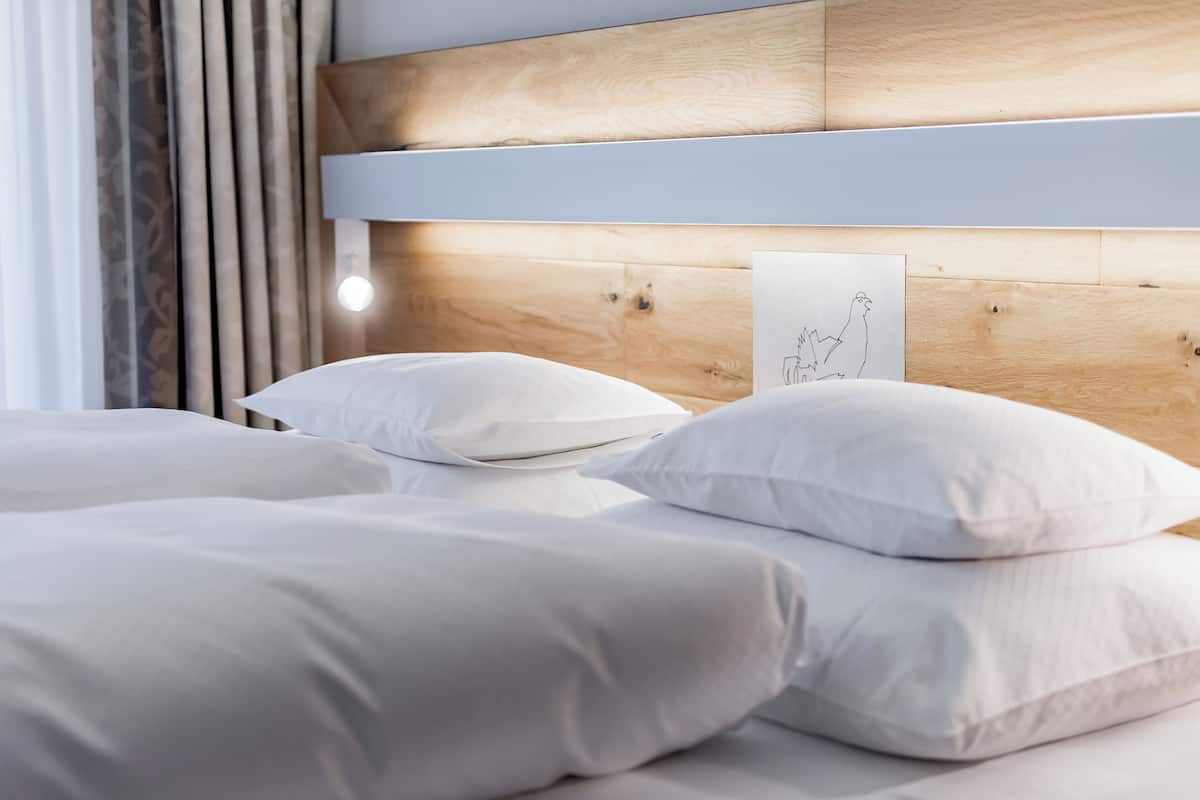Cama bem arrumada com roupa de cama branca e cabeceira com design de painel de madeira.