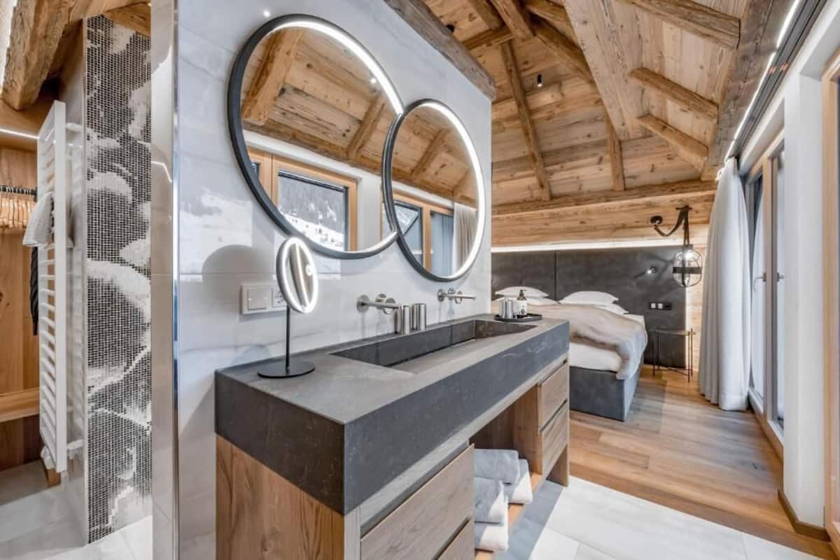 Uma casa de banho moderna com um espelho grande, lavatório e área de duche.