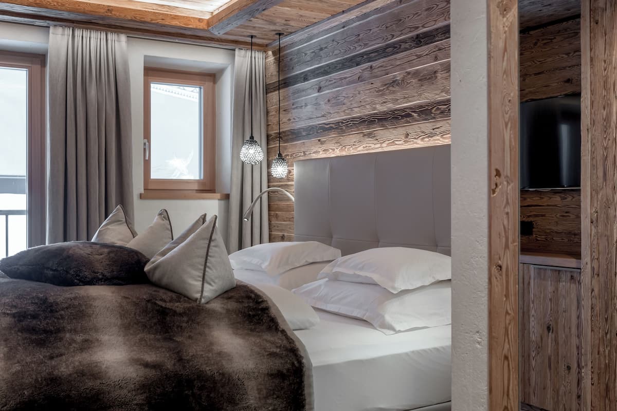 Quarto com cama, cortinas, janela e parede de madeira.