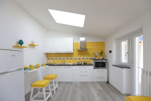 Cozinha moderna com armários brancos, painel de parede amarelo e claraboia.