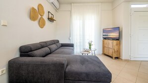 Uma sala de estar moderna com um sofá seccional, uma televisão, uma mesinha com uma planta e um armário de madeira.