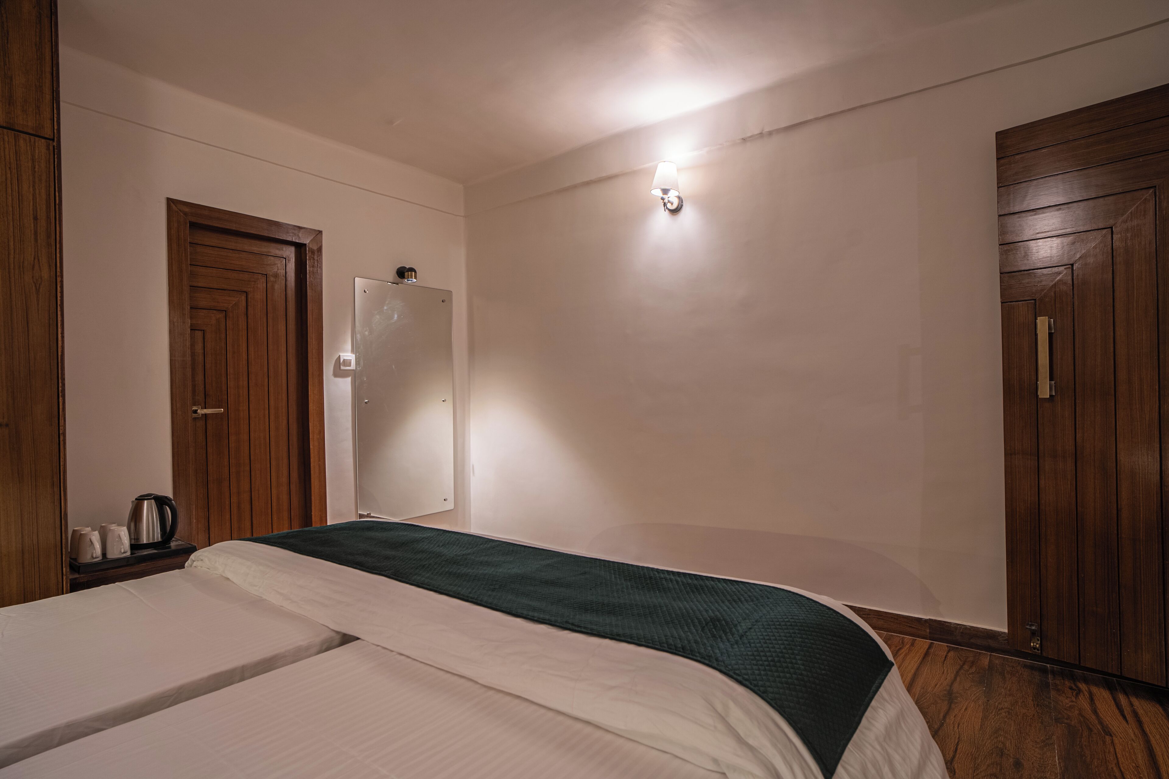 Quarto de hotel com cama, guarda-roupa, espelho e luminária na parede.