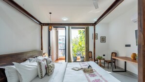 Quarto com cama, mesa de cabeceira e vista para o exterior.