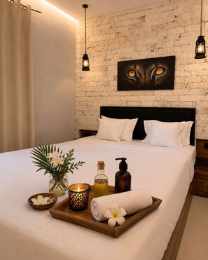 Cama bem arrumada com bandeja de madeira, uma vela e artigos de higiene.