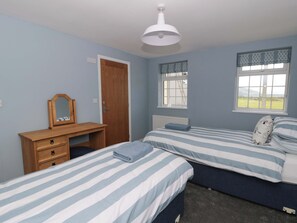 Quarto com duas camas, penteadeira de madeira, espelho e janela com vista.