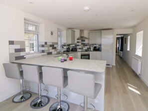 Cozinha moderna com ilha central, banquetas e vista para a área de jantar adjacente.