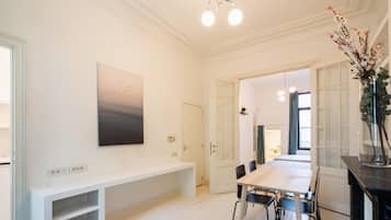 Um interior moderno com um banco branco, uma mesa de jantar com cadeiras, um quadro e um vaso com flores.