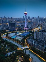Paisagem urbana com uma torre imponente, um rio e edifícios altos ao redor.