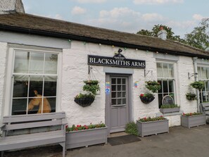 Um edifício branco com uma placa que diz 'Blacksmiths Arms'.