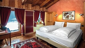 Um quarto de madeira com uma cama, cortinas, uma escrivaninha e uma janela.