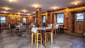 Restaurante com paredes de madeira, soalho em azulejos e várias mesas de jantar.