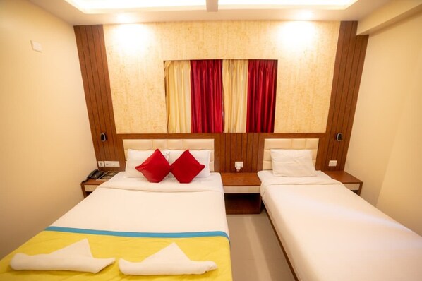Quarto de hotel com duas camas, uma cabeceira de madeira, um telefone e uma mesa de cabeceira.