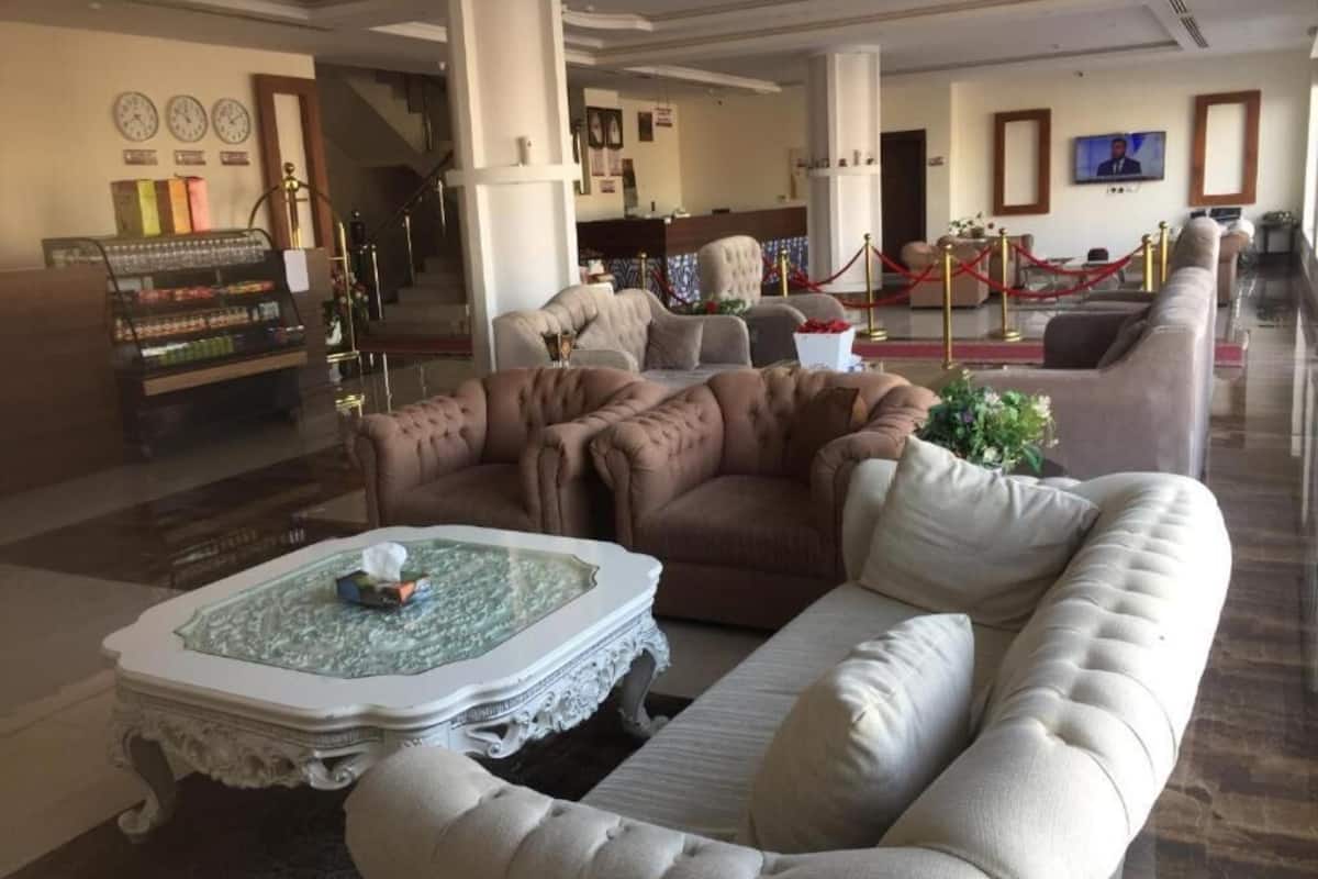 Um hall com balcão de recepção, escada, tela de televisão e área de estar com uma mesa de centro.
