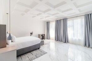 Quarto moderno com cama grande, escrivaninha e cadeira.