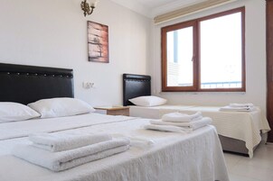 Quarto de hotel com duas camas, uma mesa de cabeceira, uma janela e um quadro na parede.