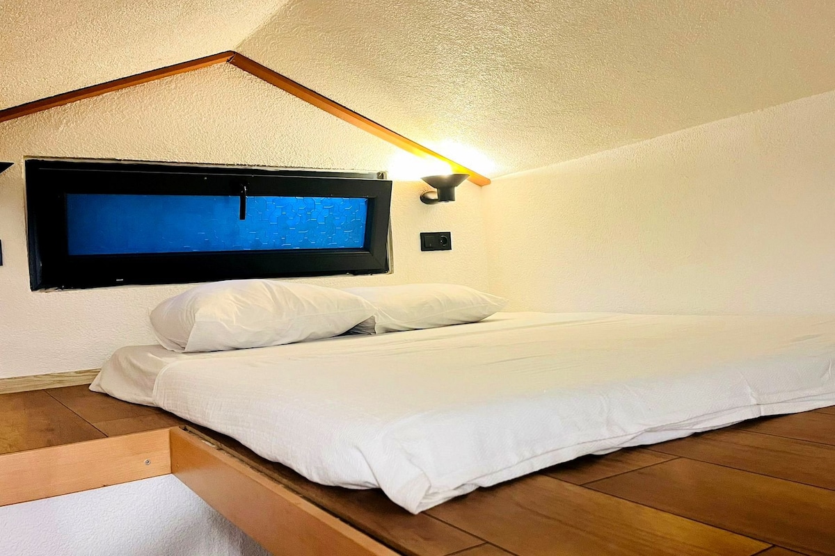 Quarto com cama, janela e luminária na parede.