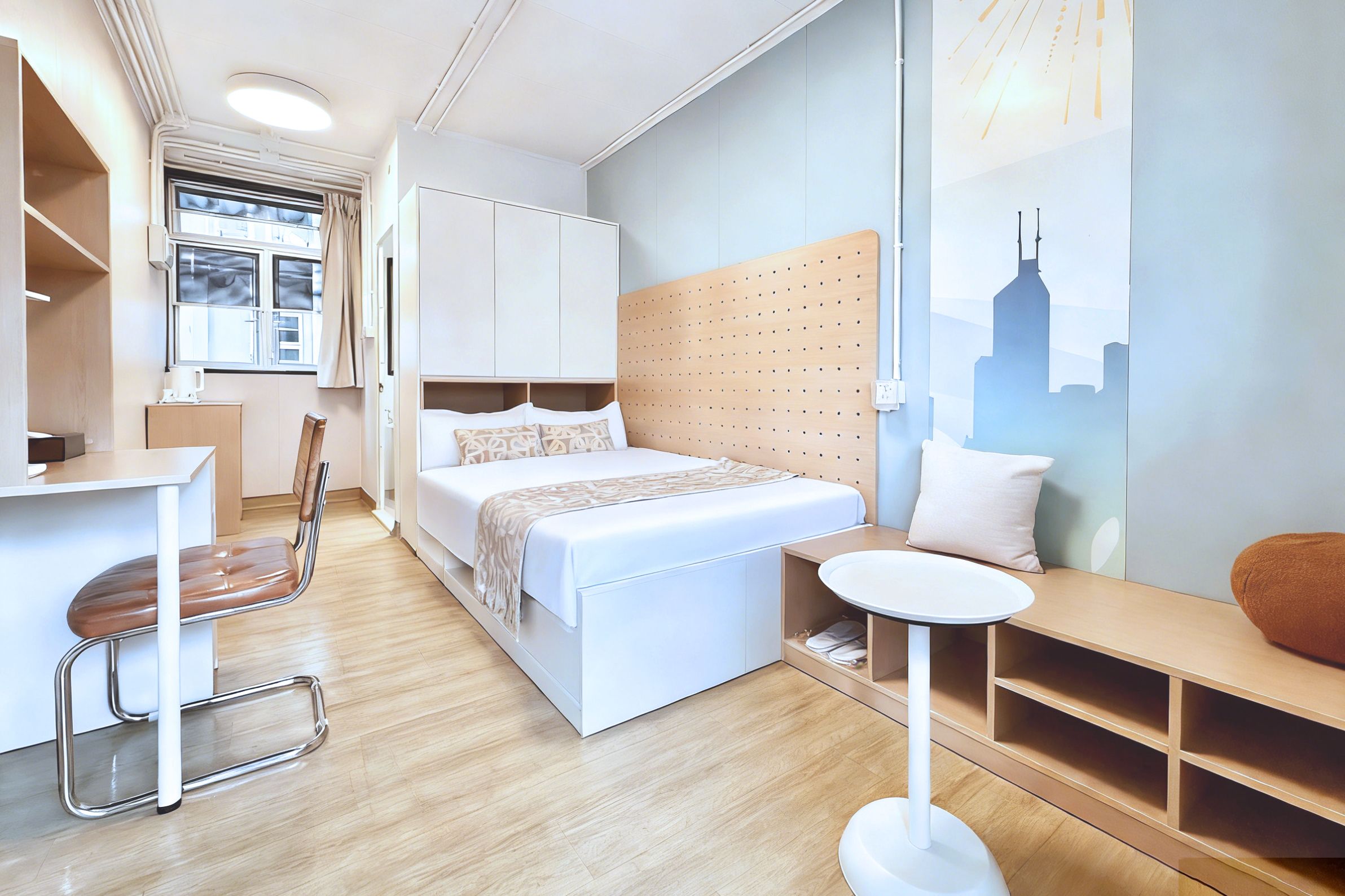 Quarto de hotel moderno com cama, escrivaninha, cadeira, mesa redonda e um mural com vista para a cidade.
