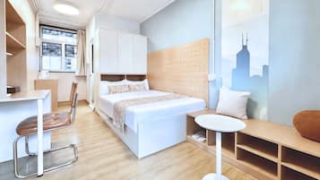 Quarto de hotel moderno com cama, escrivaninha, cadeira, mesa redonda e um mural com vista para a cidade.