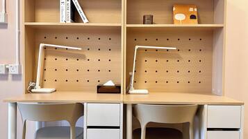 Um espaço de trabalho com duas mesas, cada uma com um painel de avisos, uma luminária de mesa e uma caixa de lenços.