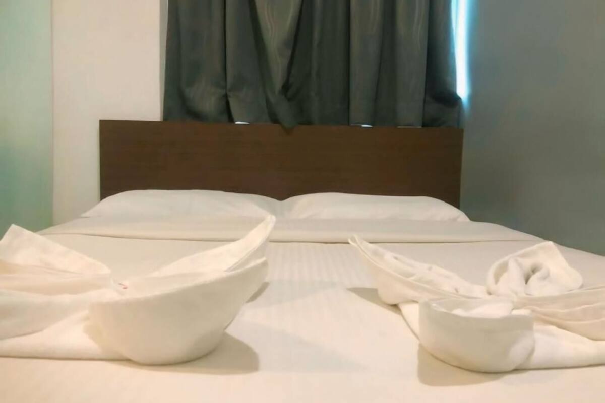 Cama bem arrumada com almofadas e um recipiente com artigos de higiene pessoal.