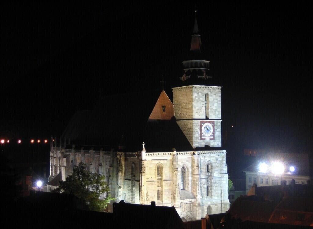 Um edifício histórico com uma torre imponente e um relógio, iluminado à noite.