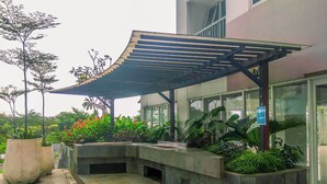 Área externa coberta com vasos de plantas e entrada de um edifício.