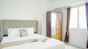 Quarto de hotel com cama, guarda-roupa e janela com cortinas.