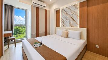 Quarto de hotel moderno com uma cama grande, uma escrivaninha e vista para o verde.