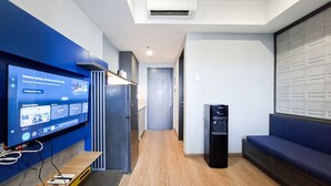 Uma sala de estar moderna com televisão de tela plana, um sofá, uma máquina de café e piso de madeira.