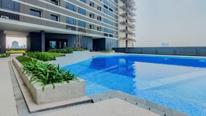 Um edifício moderno com piscina, rodeado por vegetação e céu claro.