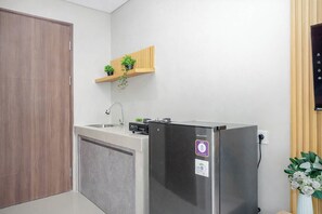Cozinha compacta com geladeira embutida, pia e prateleira de madeira com plantas.