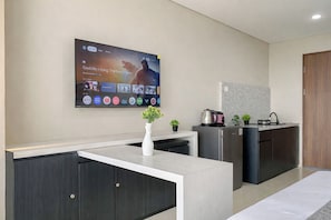 Uma cozinha moderna com uma televisão de tela plana na parede exibindo uma sugestão de filme.