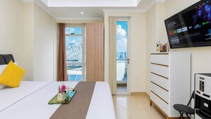 Quarto de hotel com cama, televisão, secretária e vista para a cidade.