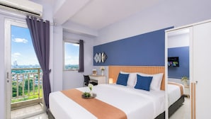 Quarto de hotel com cama, escrivaninha, cadeira, televisão e vista da cidade.