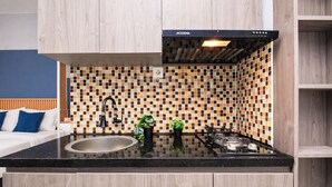 Cozinha moderna com bancada preta, fogão a gás, coifa preta e painel de azulejos.