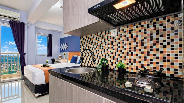 Quarto de hotel moderno com varanda, cozinha com painel de azulejos e cama com vista.