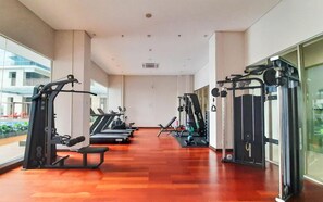 Uma academia ampla com esteiras, aparelhos de musculação e um banco.