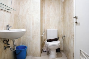 Casa de banho com lavatório branco, sanita e balde azul.