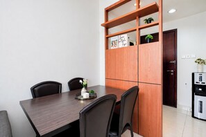 Uma sala de jantar com uma mesa de madeira, quatro cadeiras, um vaso decorativo e um dispensador de água.