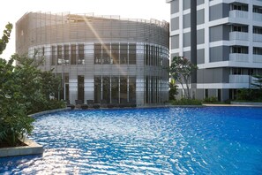 Um edifício moderno com fachada curva e piscina em frente.