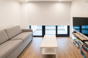 Uma sala de estar moderna com um sofá, uma mesa de centro, uma televisão e uma estante.