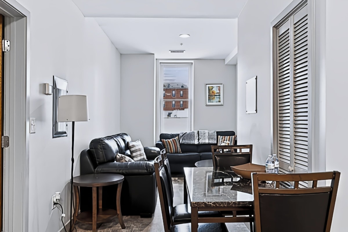 Uma sala de estar moderna com um sofá, uma mesa de centro e um espaço de jantar com cadeiras.