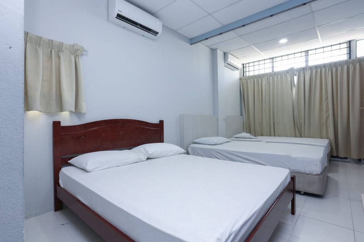 Quarto de hotel com duas camas, ar condicionado, janela com cortinas e iluminação embutida no teto.